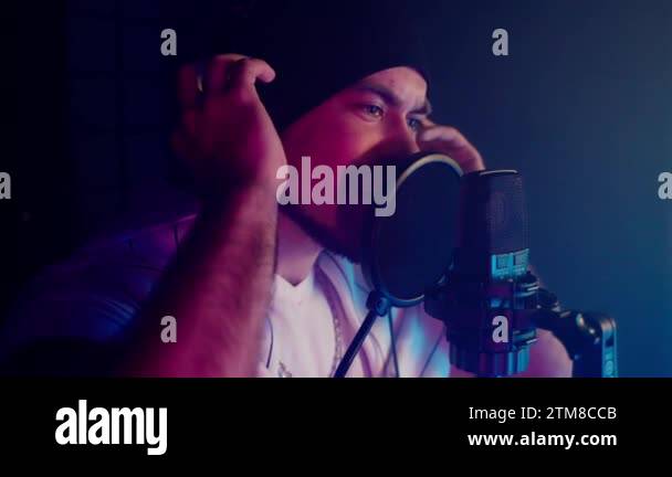 emotional man is singing song to microphone in recording studio, making ...