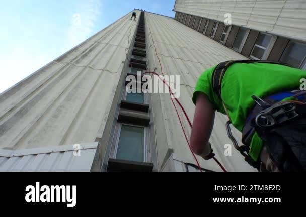 Fearless guy descend down from high skyscraper and service staff care ...