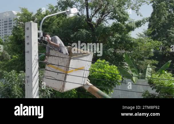 Worker on height lifting platform installing new street light bulb ...