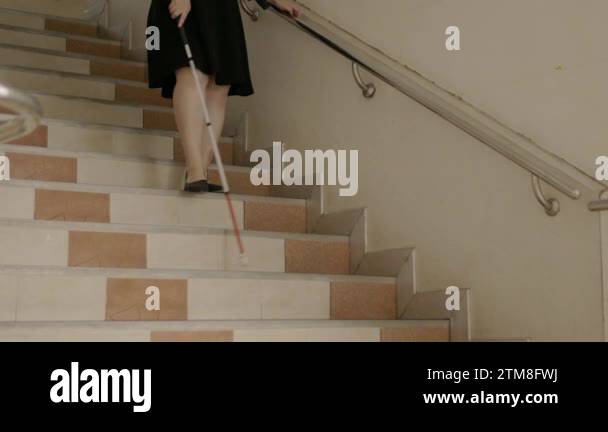 Woman with blindness disability walking down stairs using blind walking ...