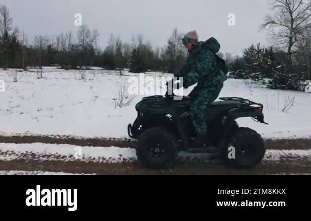 Woman riding on an ATV through the snowy landscape, side view. Quad ...
