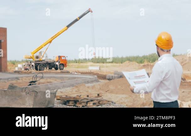 Male bearded construction boss dressed in a hard hat controls ...