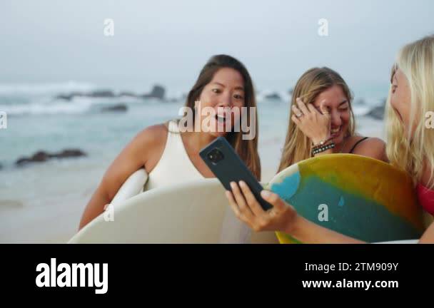 Cheerful multiracial surfer girls in bikini taking selfies holding ...