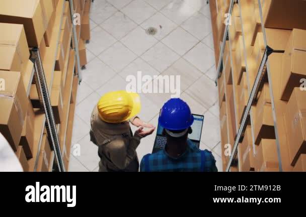 Diverse employees analyzing inventory list on laptop, counting products ...