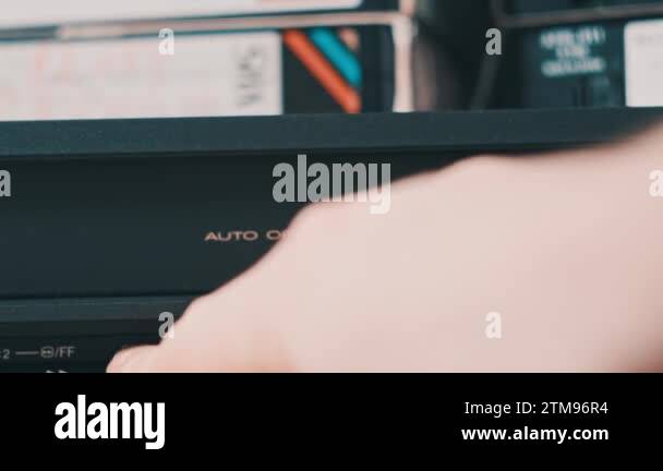 Eject VHS tape cassette from VCR player. Male hand pushes a button and ...