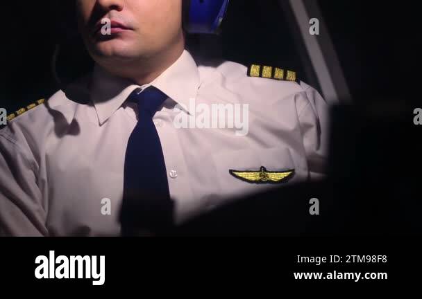 Man in civil aviation pilot uniform and headset navigating aircraft at ...
