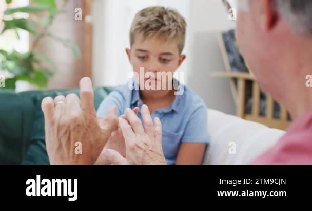 Happy caucasian grandfather and grandson sitting on sofa and using sign ...