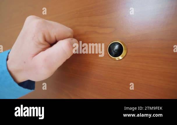 Knocking at the door. Hand knocks on the closed door with a peephole ...