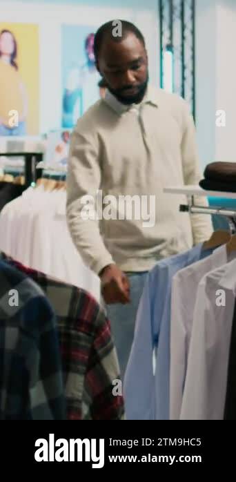 Vertical video: Modern man shopping for formal wear in clothing store ...