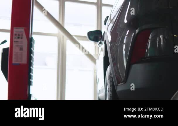 Passenger car is lowered on a car lift. Close up view of service lift ...