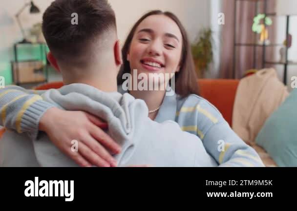 Portrait of woman embracing, hugging man, looking at camera over his ...