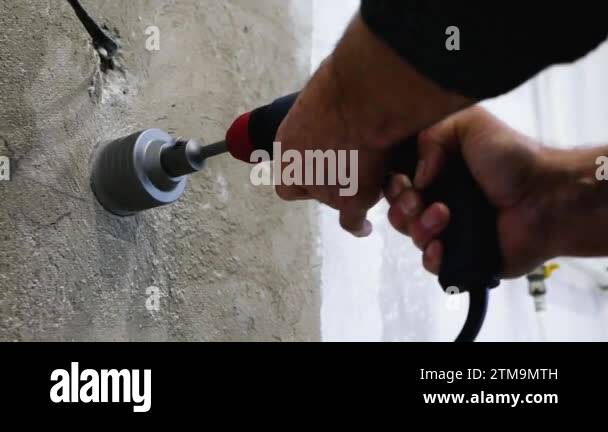 Installation of socket boxes in the wall. A male worker is drilling a ...