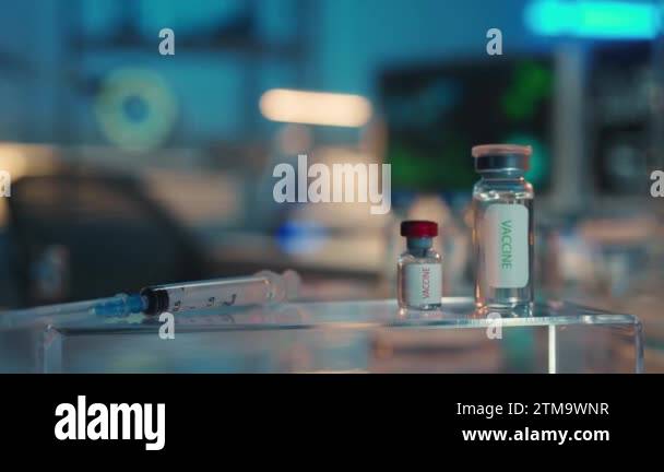 In the foreground are glass vials with a medical vaccine and a syringe ...