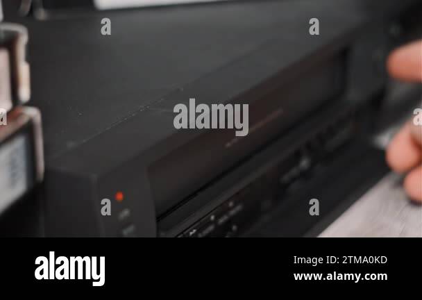 Eject VHS tape cassette from VCR player. Male hand pulls out VHS from a ...