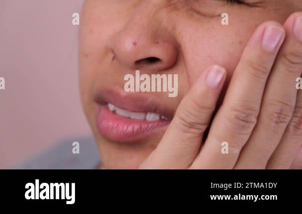 Close-up of woman having toothache and her hands touching her face ...