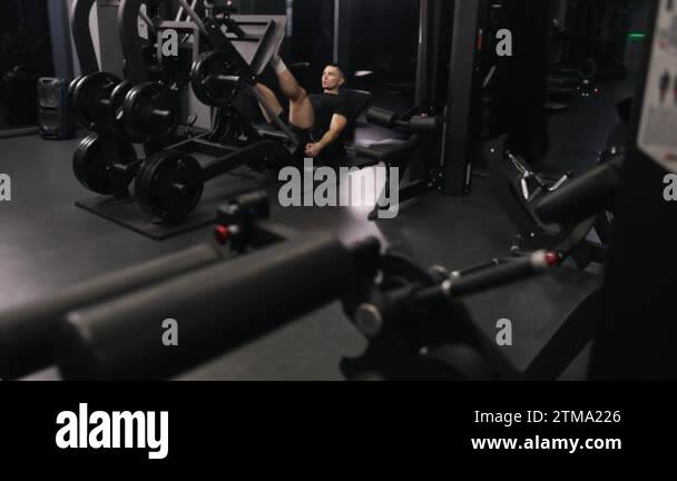 Sportsman uses, Leg exercise machine, Gym workouts. Fit male athlete ...