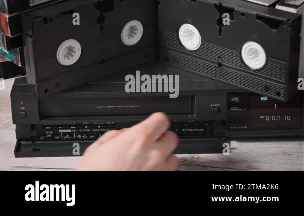 Eject VHS tape cassette from VCR player. Male hand pulls out VHS from a ...
