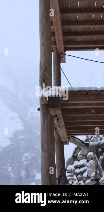 Thick and slow snowfall in front of a wooden structure with a misty ...