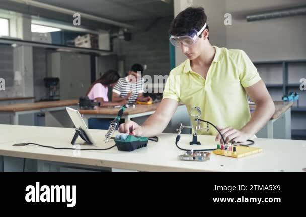 College Student working on electronics circuit, learning science ...