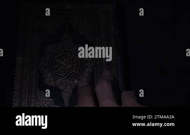 Opening the Muslim holy book. Cover of the book with gold lettering ...