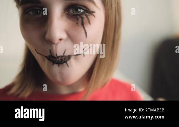 Preteen girl with spooky Halloween makeup posing at camera closeup ...
