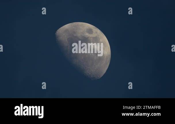Bright full moon behind fast moving thin layer of clouds on night blue ...