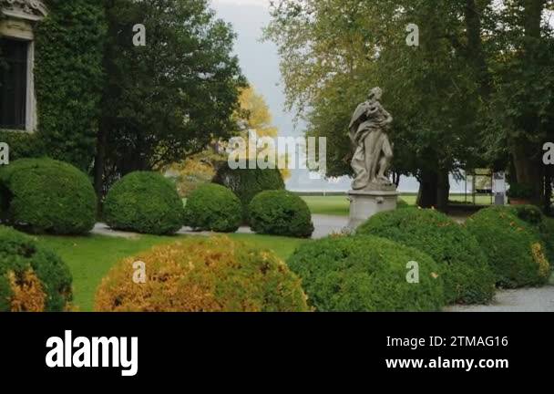 Antique human statue copy in city park among trees near mansion ...