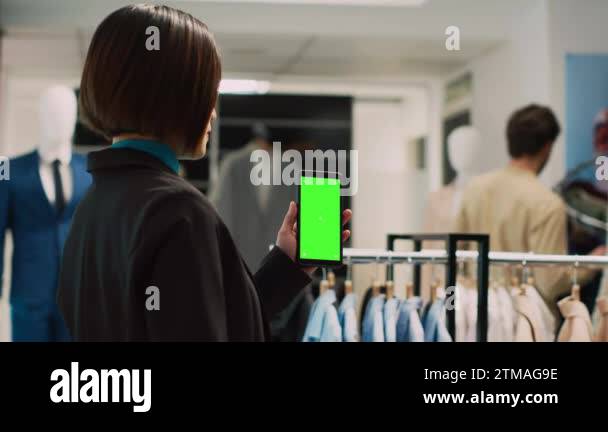 Young Assistant Using Blank Greenscreen Template Showing Chroma Key Display In Trendy Clothing