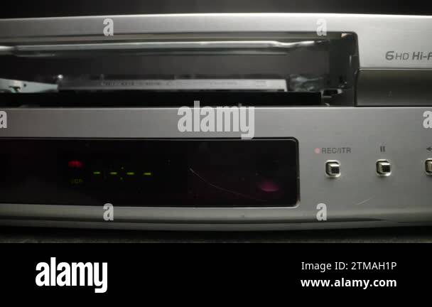 Inserting and removing a VHS cassette into an old VCR. Dolly shot ...