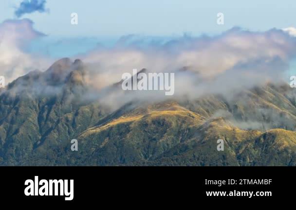Misty clouds moving fast in sunny summer morning over mountains ridge ...