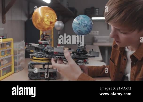 Serious Caucasian teen boy working on robotic solar system model ...