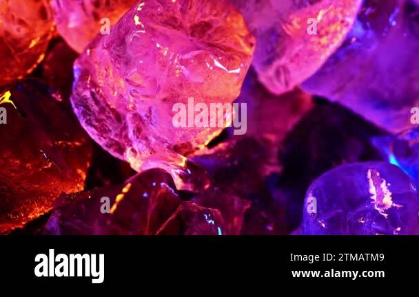 Multi-colored paint spreads over the surface of the ice cubes and flows ...