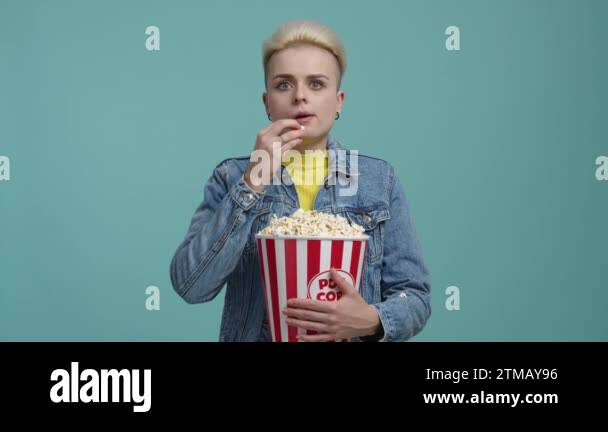 Close-up shot of caucasian woman eating fresh, delicious popcorn in the ...