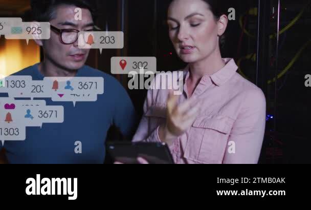 Animation of social media icons and numbers over diverse it technicians by computer servers ...