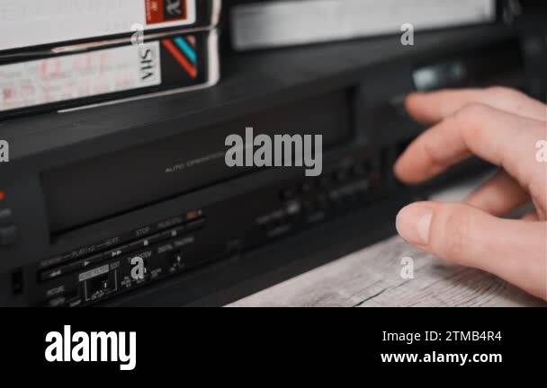 Eject VHS tape cassette from VCR player. Male hand pulls out VHS from a ...