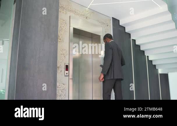 An african american businessman in a formal suit summons an elevator by ...