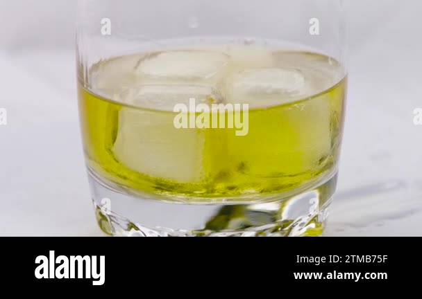 Glass of whiskey with ice cube. Alcohol pouring in the glass from the ... Glass of whiskey with ice cube. Alcohol pouring in the glass from the ...