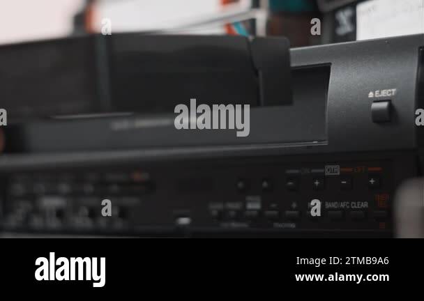 Eject VHS tape cassette from VCR player. Male hand pulls out VHS from a ...