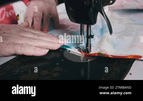 Old female hands of seamstress sew at a retro sewing machine at home in ...