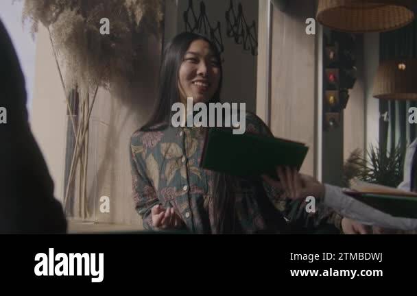Asian woman sits in cafe, talks with African American man and looks ...