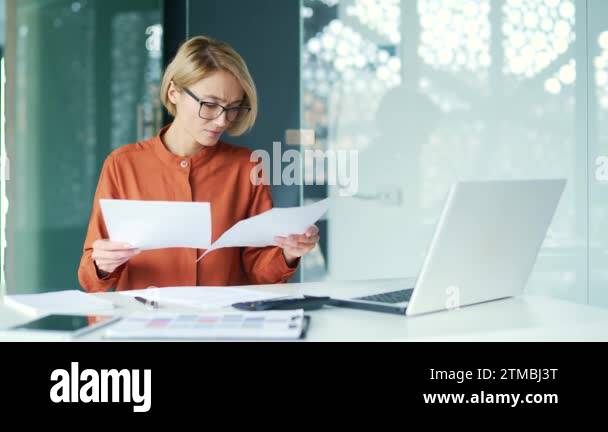 Confused young female accountant having difficulty with paper work ...