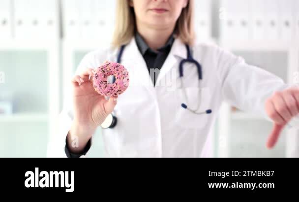 Dietitian woman doctor holding sweet donut and negative sign with hand ...