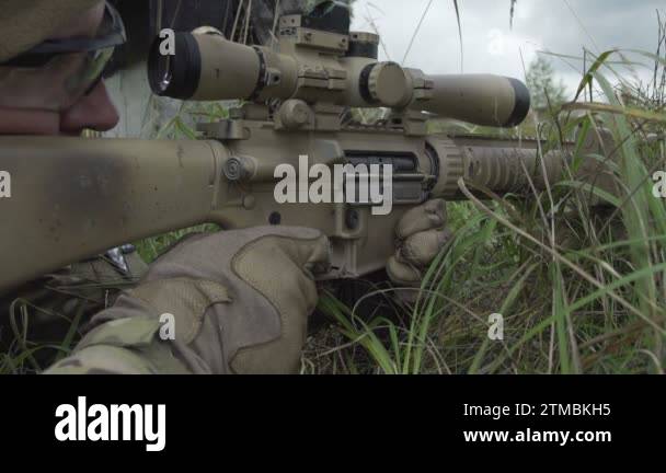 Sniper lies behind cover in the grass with a gun in his hand and shoots ...