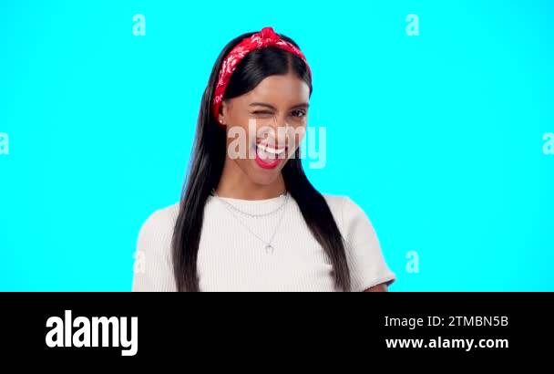 Happy woman, face and wink on blue background, laughing and flirting in ...
