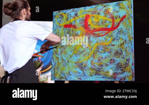 Charismatic talented beautiful artist approaches his canvas and uses ...