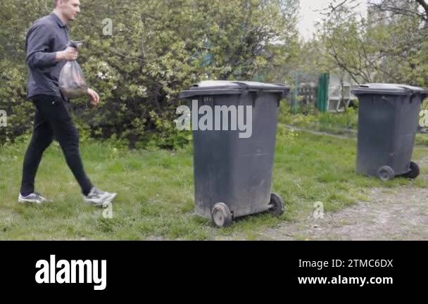 Man throwing out black eco-friendly recyclable trash bag in to big ...
