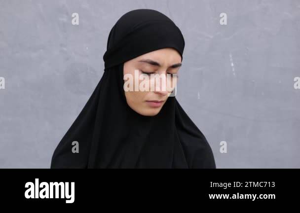 Calm, modest woman in black hijab covering head and hiding her hair ...