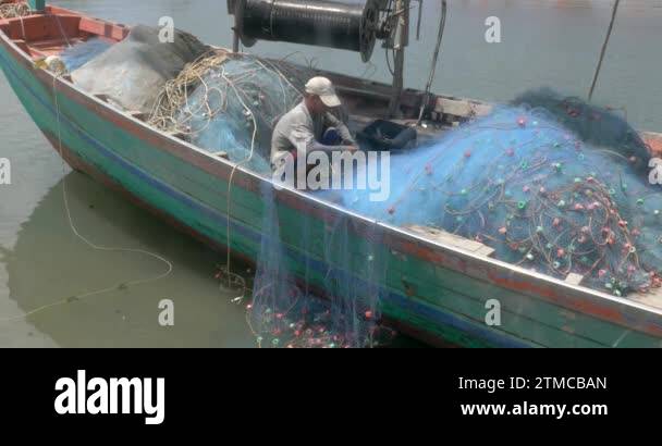 Sihanoukville , Cambodia - 04.22.2023 ; Fisher removing enmeshed fish ...