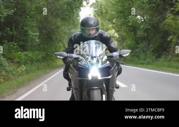 Motorcyclist travel at motorcycle on forest country road. Man in helmet ...