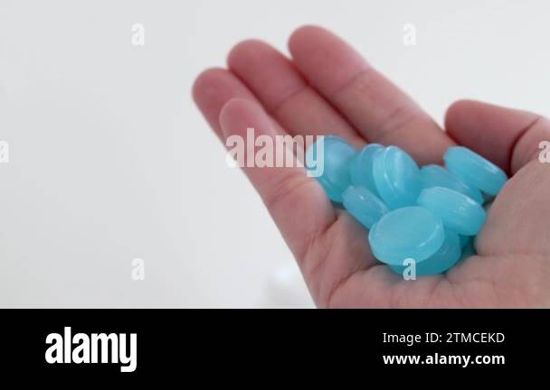 blue candy for sore throat treatment lozenges in woman hand or putting ...